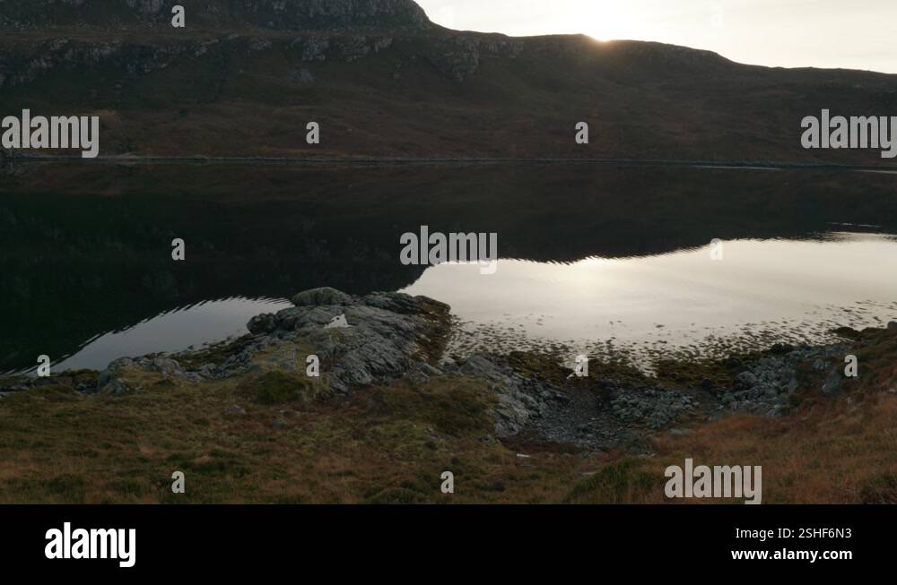 A slow panning tilt shot of still water in a sea loch in Scotland as ...