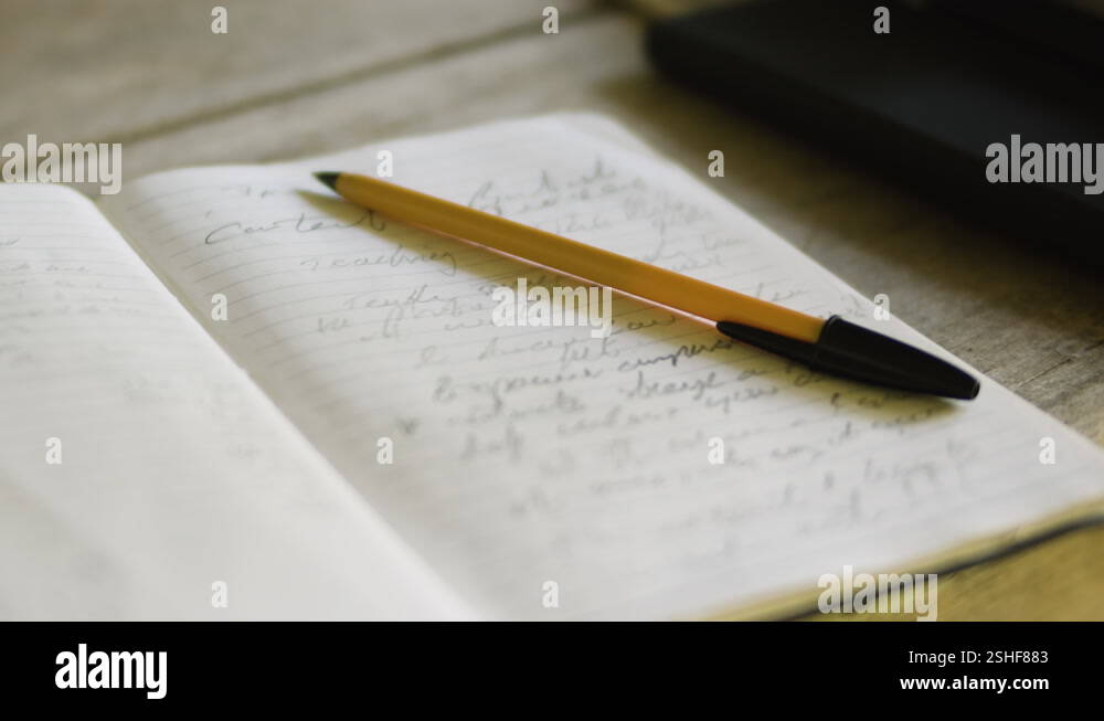 Close up pen on paper with small illegible handwriting notes in diary ...