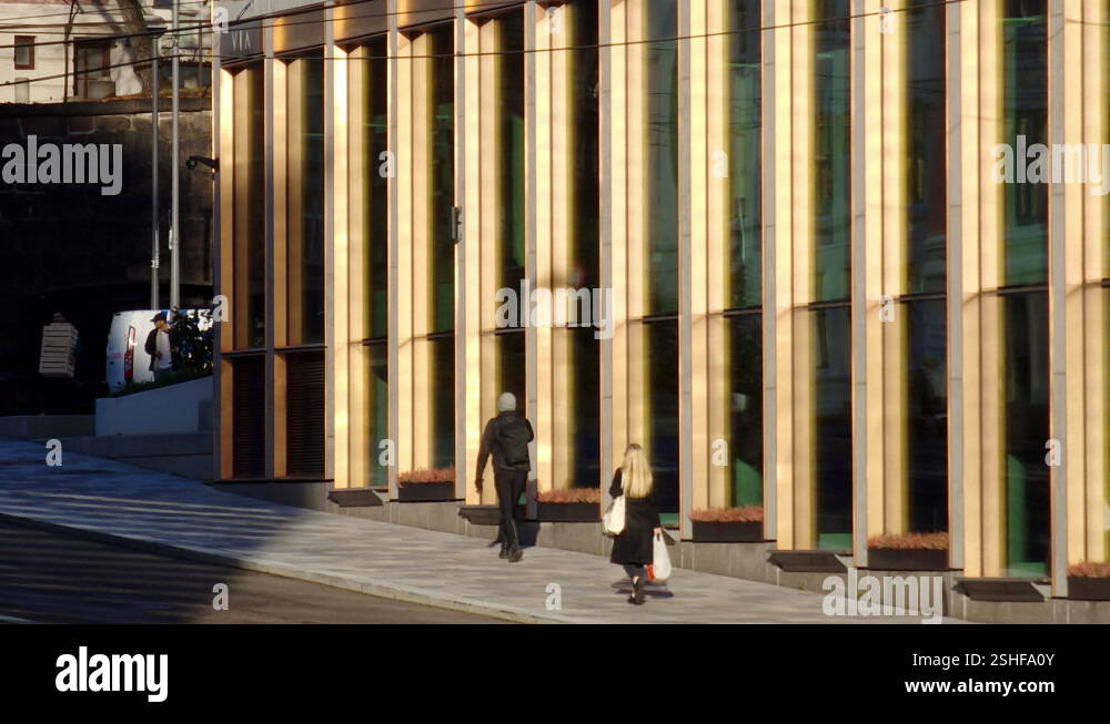 Two people walking on the sidewalk by a luxurious office building in ...