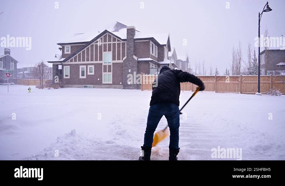 50 to 60 year old male shovelling snow out of a driveway after a winter ...