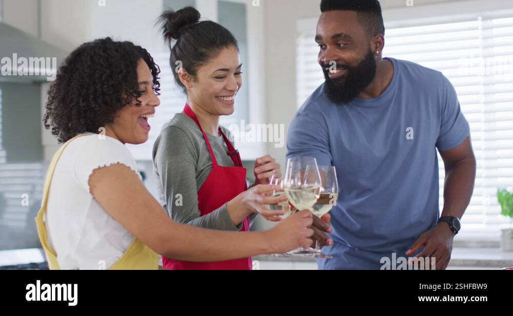 Happy diverse female and male friends drinking wine and cooking in ...