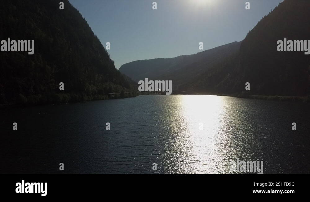 Bright silver sun beam on dark mountain lake at Three Valley Gap, BC ...