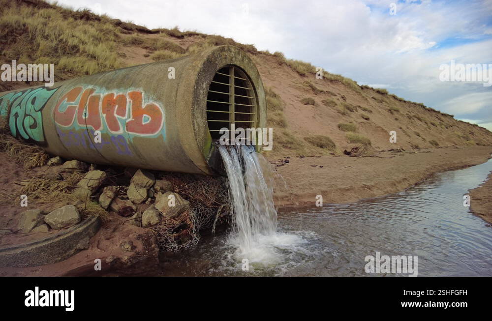 Culvert discharging water into a stream on a beach Stock Video Footage ...