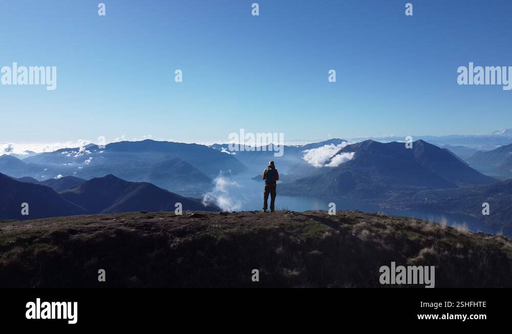 Hiker standing on the top of the mountain over lake Stock Video Footage ...