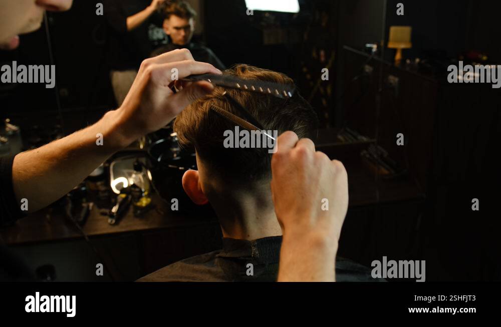 Barber use Thinning scissors and metal comb on brown wavy hair of young ...