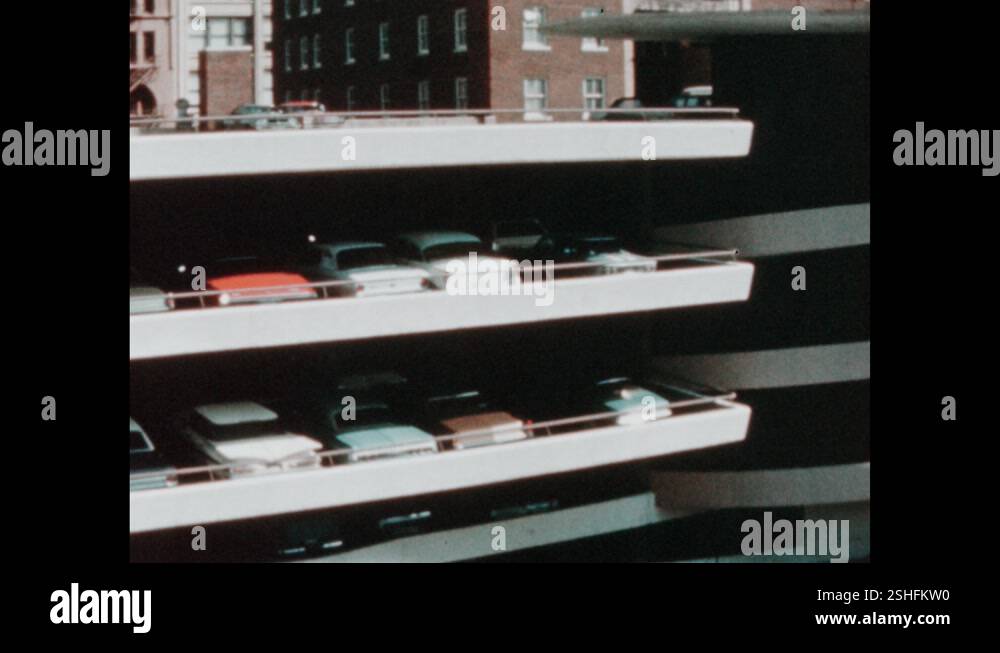 1970s: Men and women walk up and down stairs. Cars sit in multi-level ...