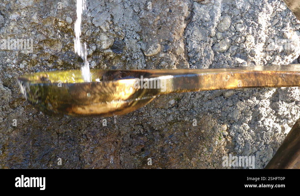 Water wheel spinning, with spoon-like blades or buckets on wooden arms ...