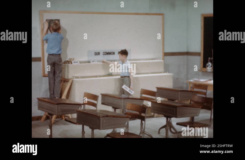 1950s: Two boys in classroom set up presentation, hang posters, set out ...