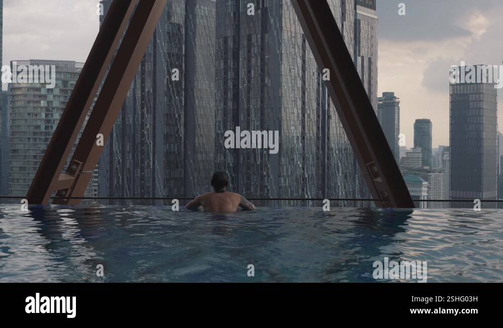 Back view of man swim and relax on the edge of the roof top swimming ...
