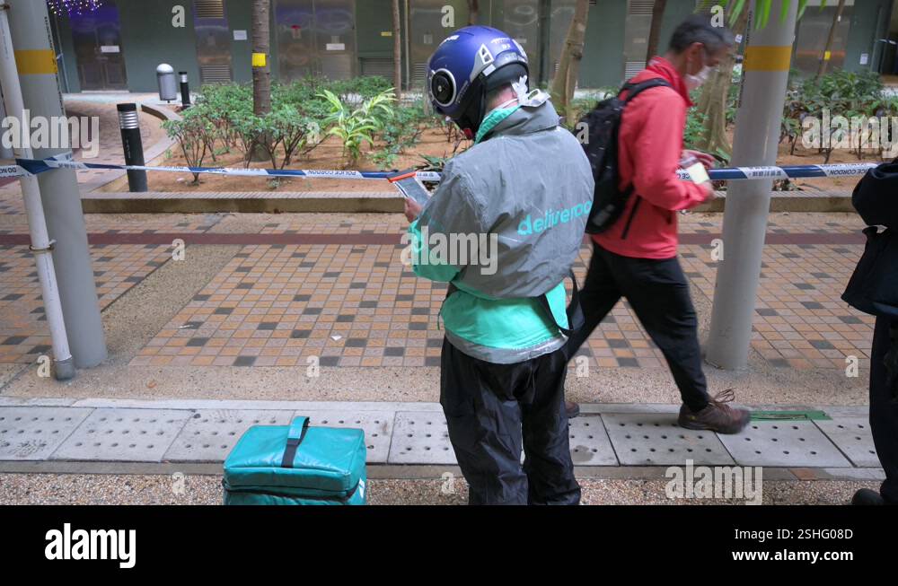 A delivery worker waits next to a police officer outside a public ...