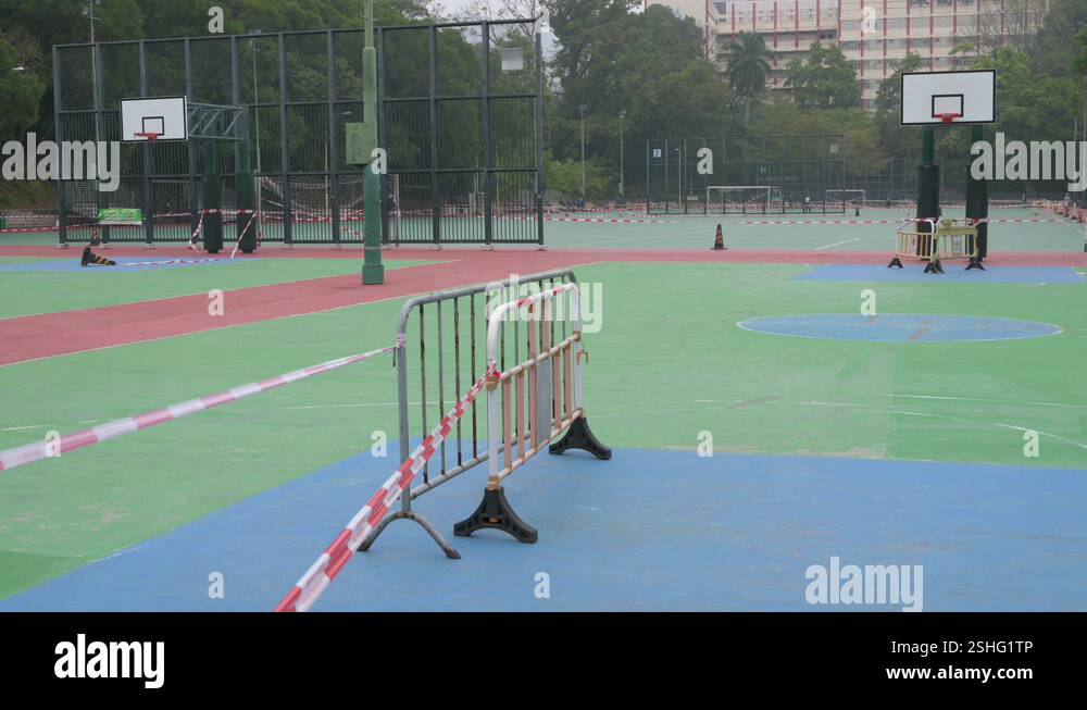 A view of a basketball court blocked by barriers at a closed playground ...