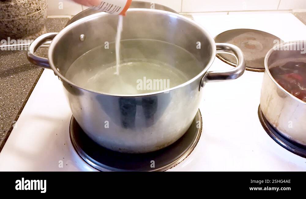 Hand add salt into simmering water in a saucepan - Cooking Spaghetti ...