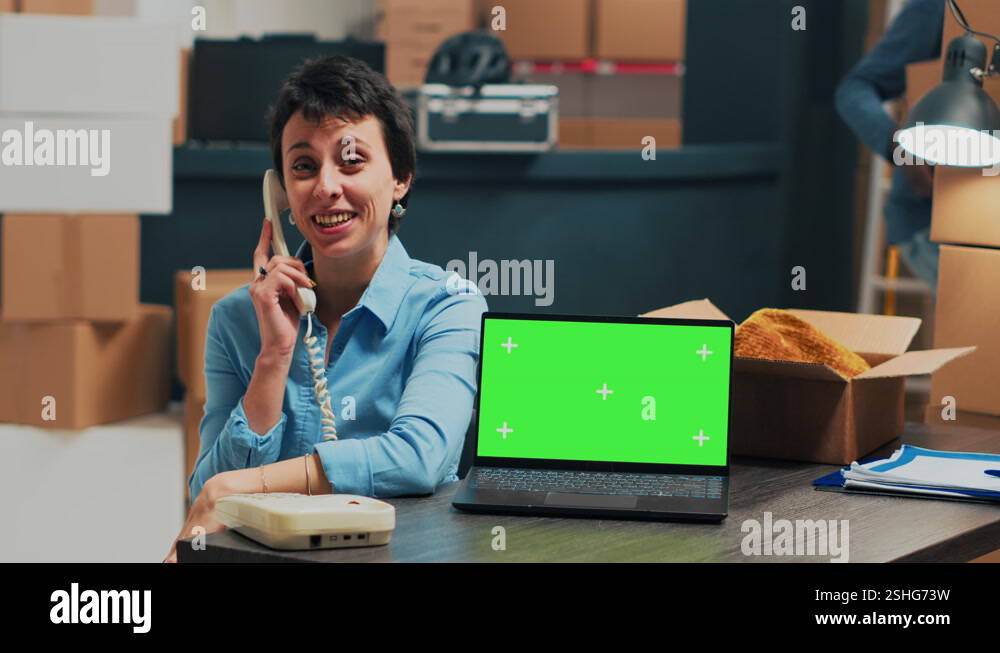 Female worker answering telephone with cord at desk using greenscreen ...
