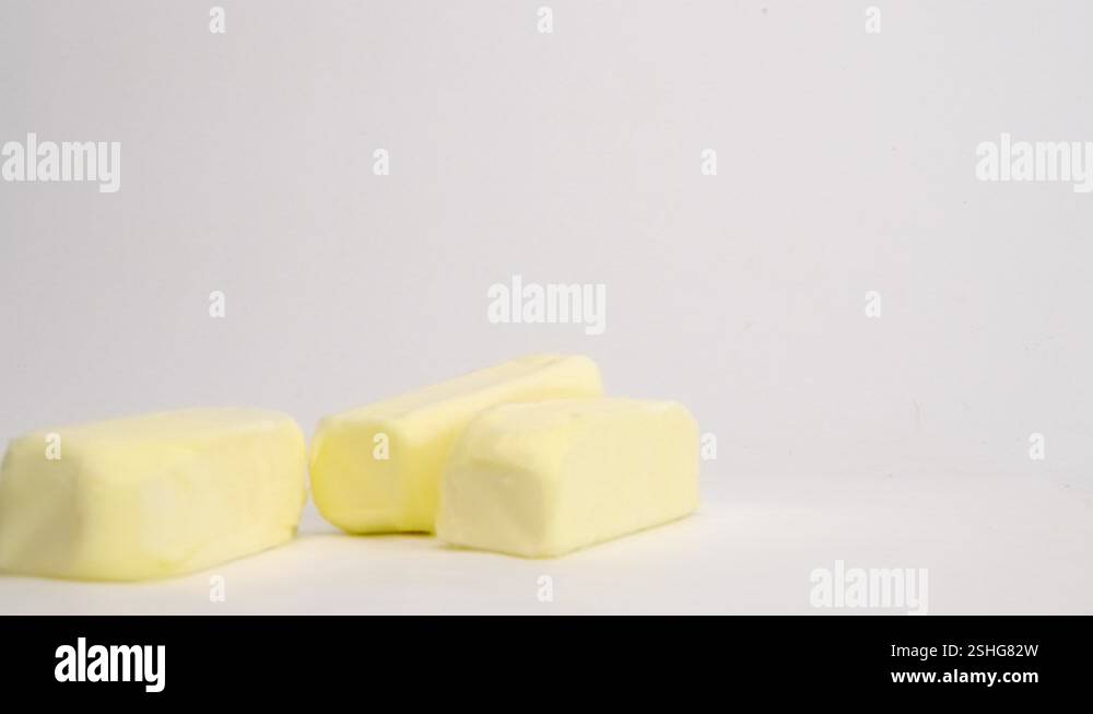 Whole, unwrapped sticks of yellow butter cubes falling and bouncing ...