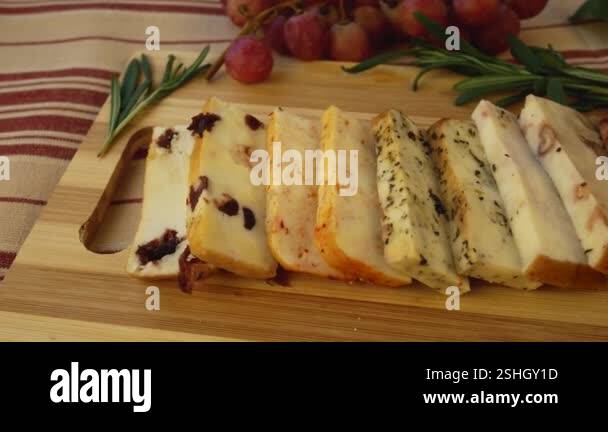 Many types of craft cheeses lie on a wooden board in sliced pieces. In ...