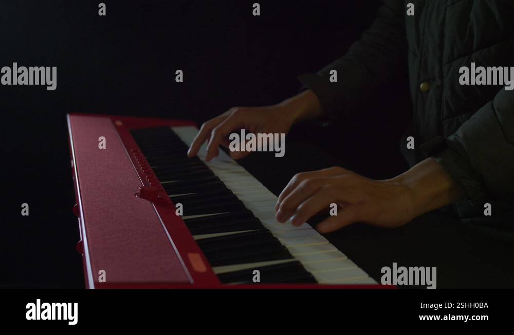 Static close-up of a person playing a piano keyboard with both hands in ...