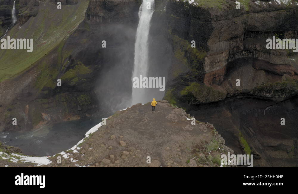 Aerial: One man wearing a yellow jacket, walking near the edge of a ...