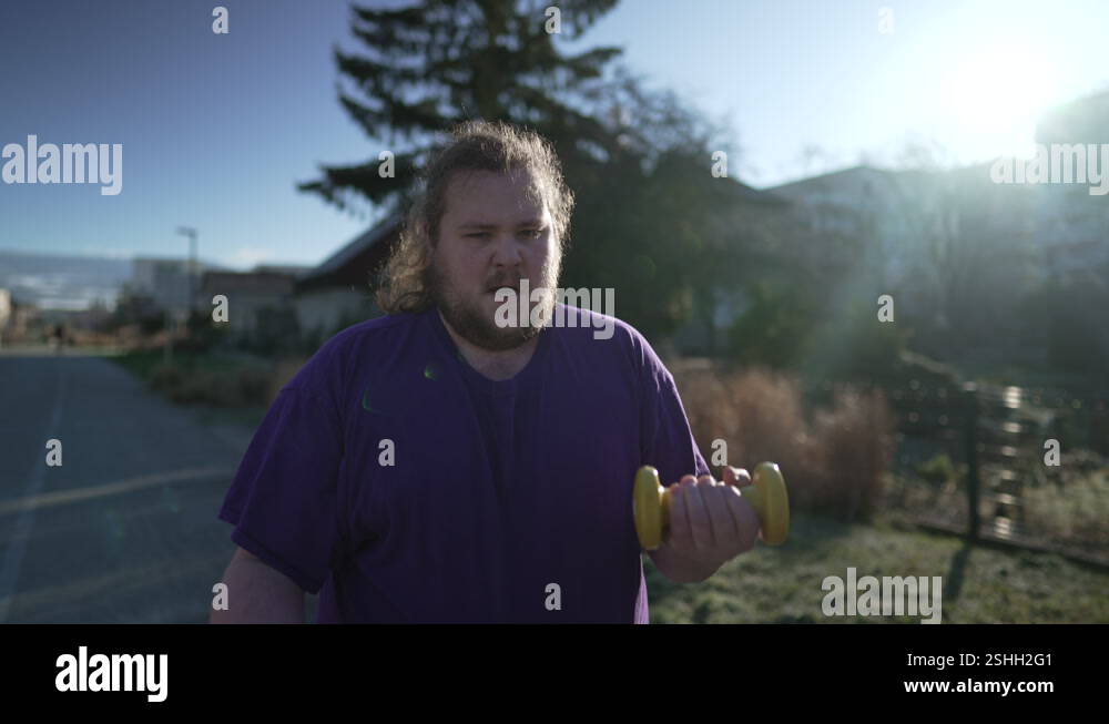 One young overweight man working out lifting dumbbells outside. A fat ...