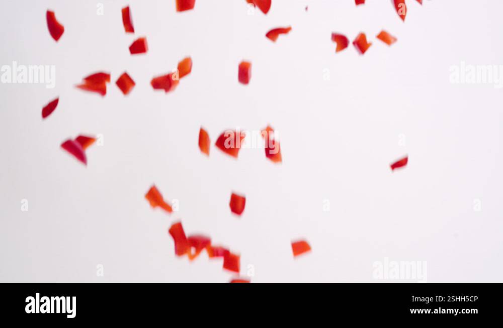 Diced cut red bell pepper vegetable chunks raining down on white ...