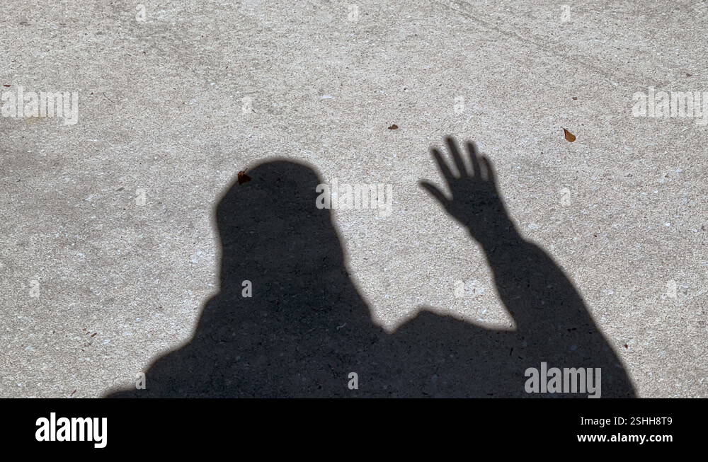 Shadow of man waving hand that is open showing all fingers, standing on ...