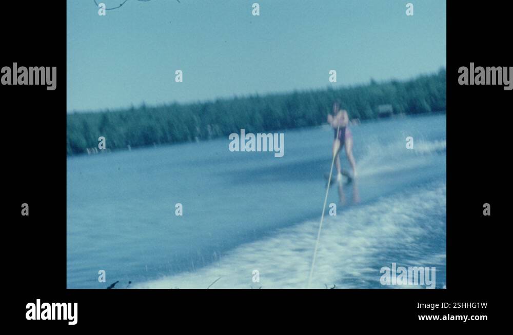 1950s: Boat speeds across lake towing water-skier. Water-skier lets go ...