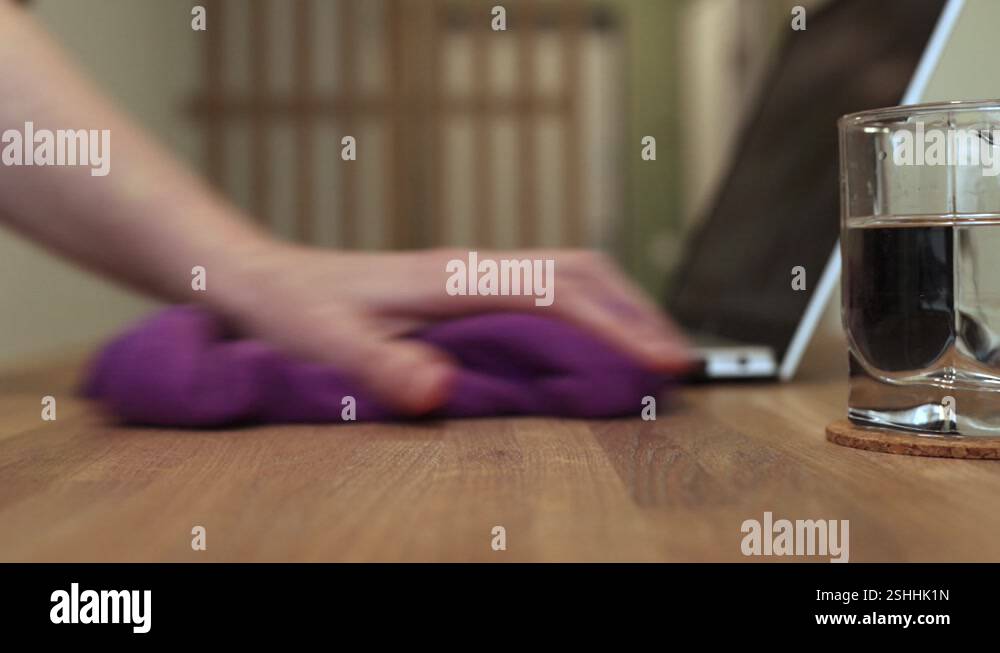 Hand with cloth cleaning workplace, wood work desk from dust on desktop ...