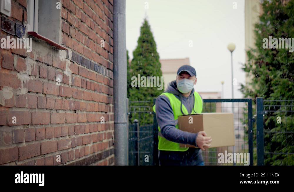 Delivery man in protective face mask for coronavirus prevention gives ...
