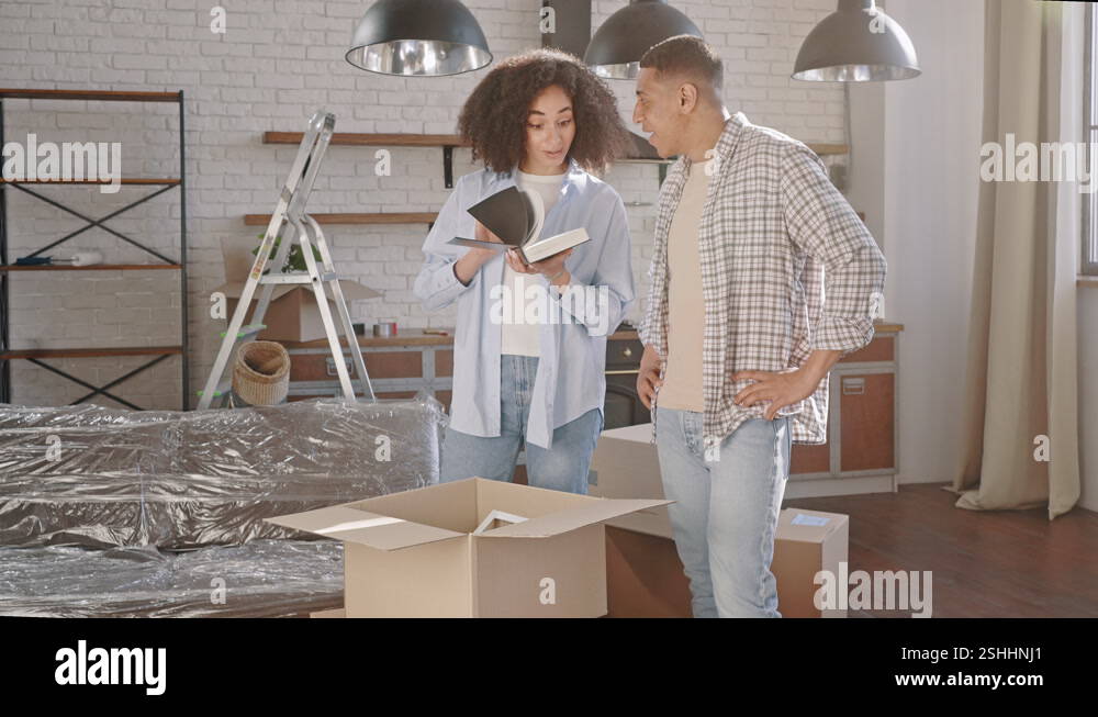 Young couple unpacking cardboard boxes while moving and rejoicing ...