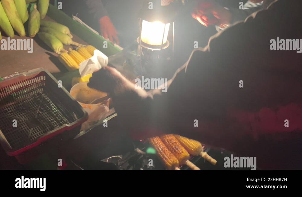 Street food vendor selling grilled corn on small food cart during Stock ...