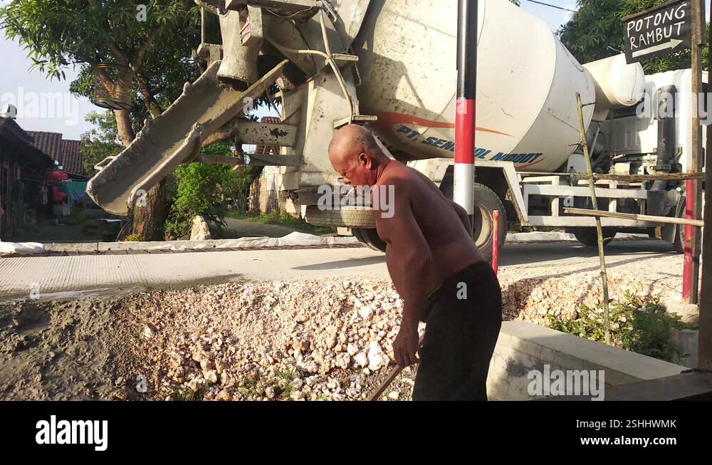 Concrete pours down mixer truck chute into large container. old man ...