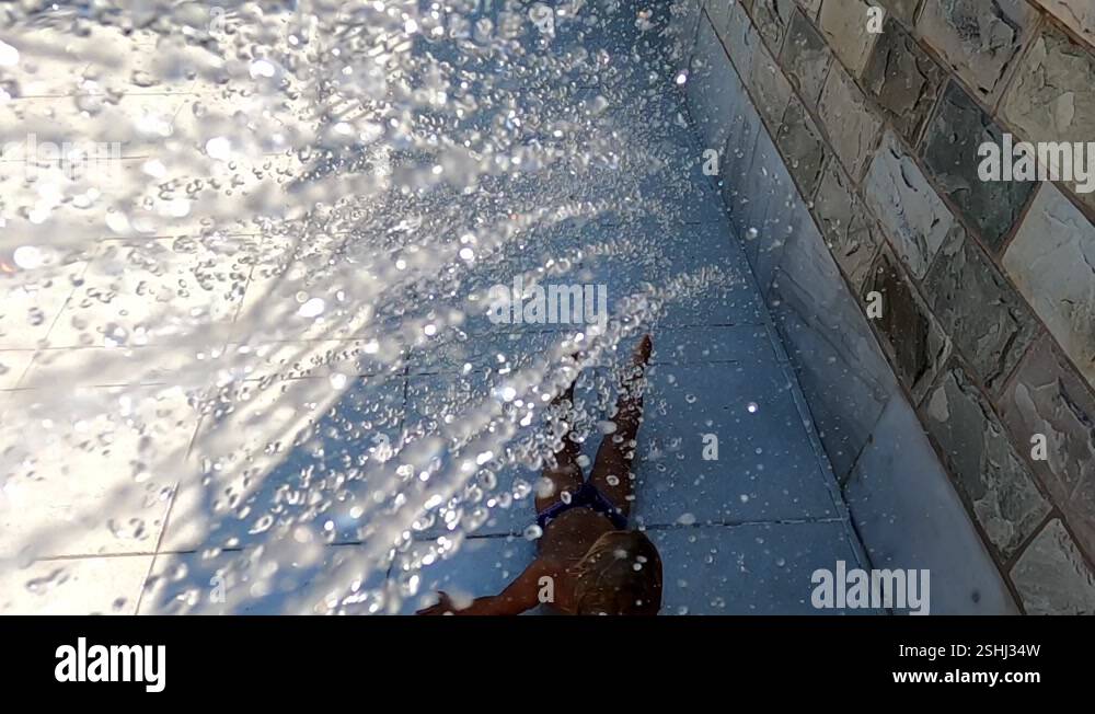 Little girl escapes from under the stream of water and falls on the ...