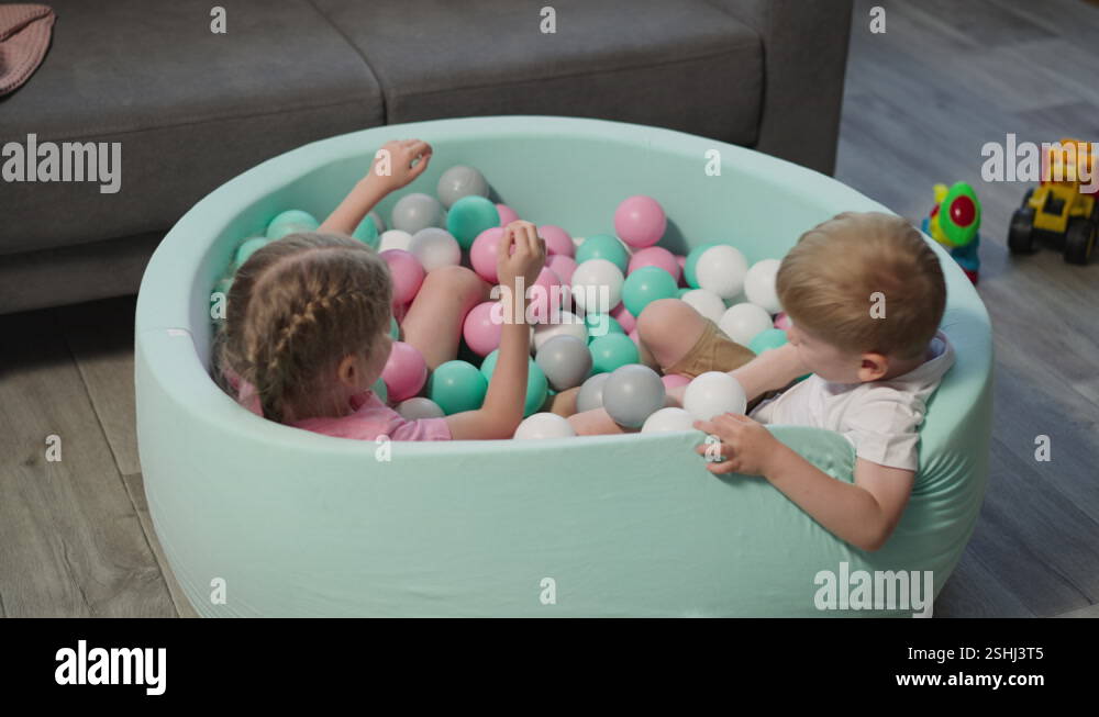 Little girl pulls brother leg playing in pool with balls Stock Video ...