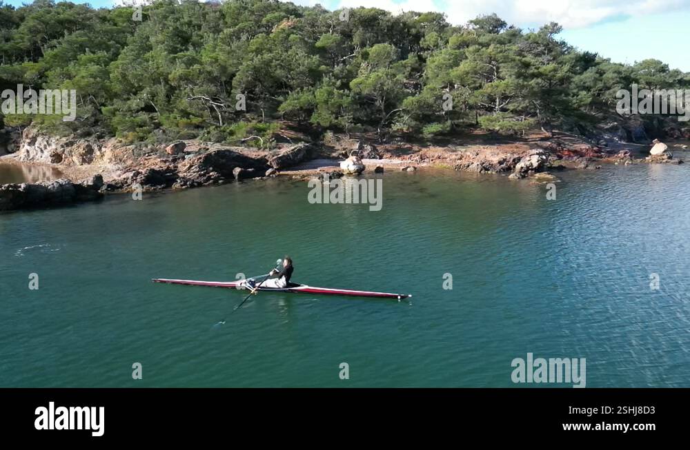 man rowing in the blue sea between mountains on a beautiful cloudy day ...