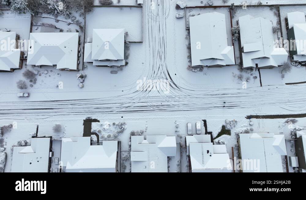 Rising overhead view of houses covered in snow during an ice storm ...
