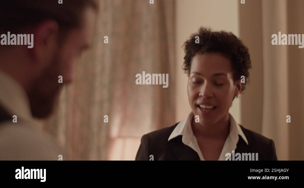 Happy ethnic woman communicating with anonymous person in hotel room ...