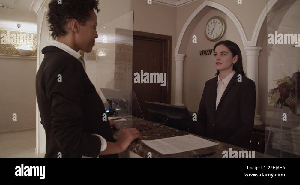 Smiling black female guest listening to receptionist during check in at ...
