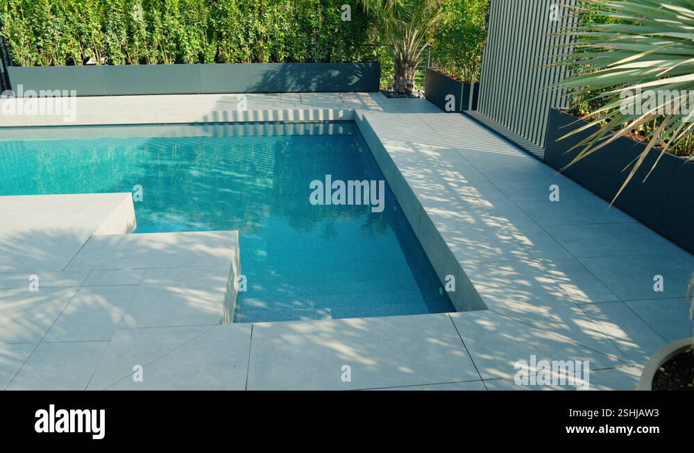 A modern Italian-style minimalist pool, with light gray tiles and ...