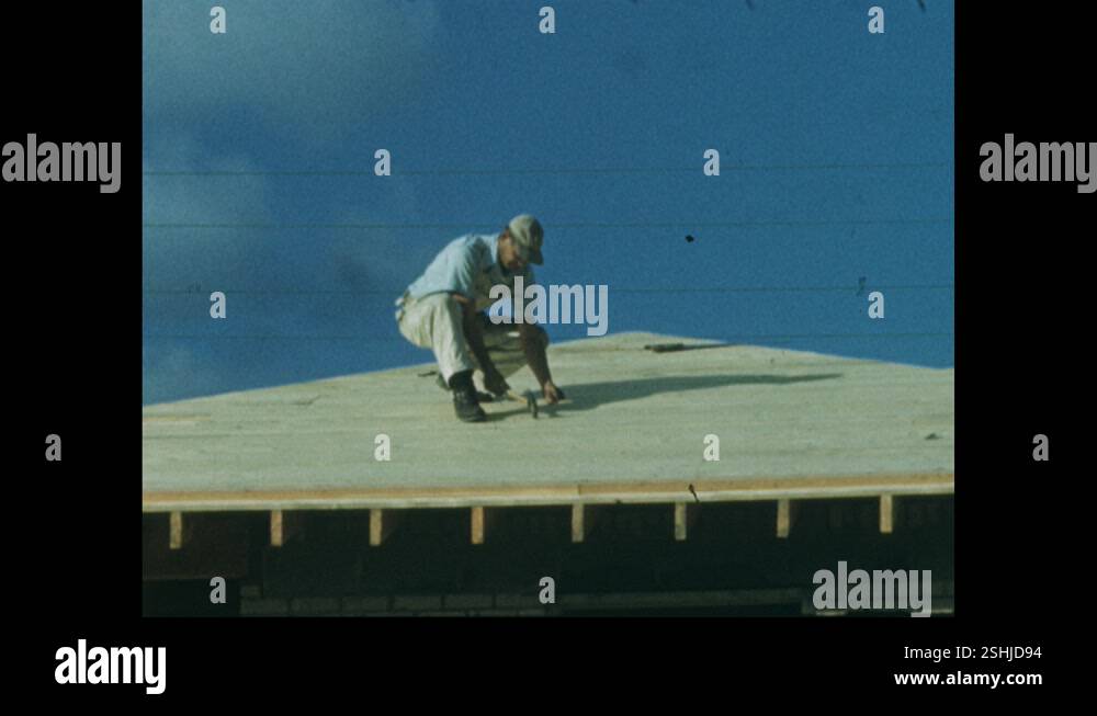 1950s:Construction worker hammers nails into roof. Boy watches men work ...