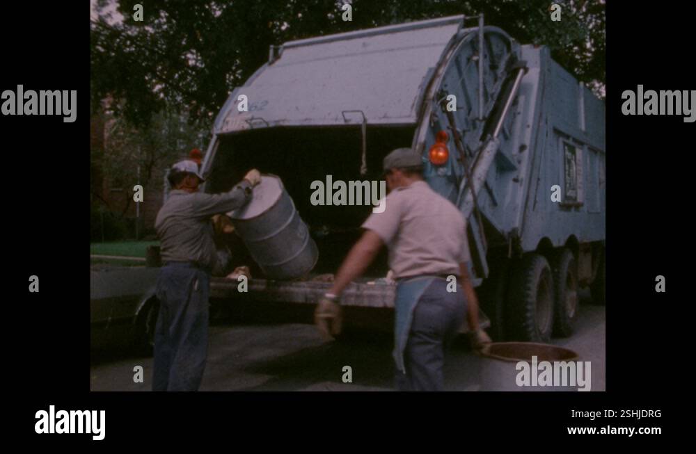 1970s: Garbage collectors dump bins into back of garbage truck ...