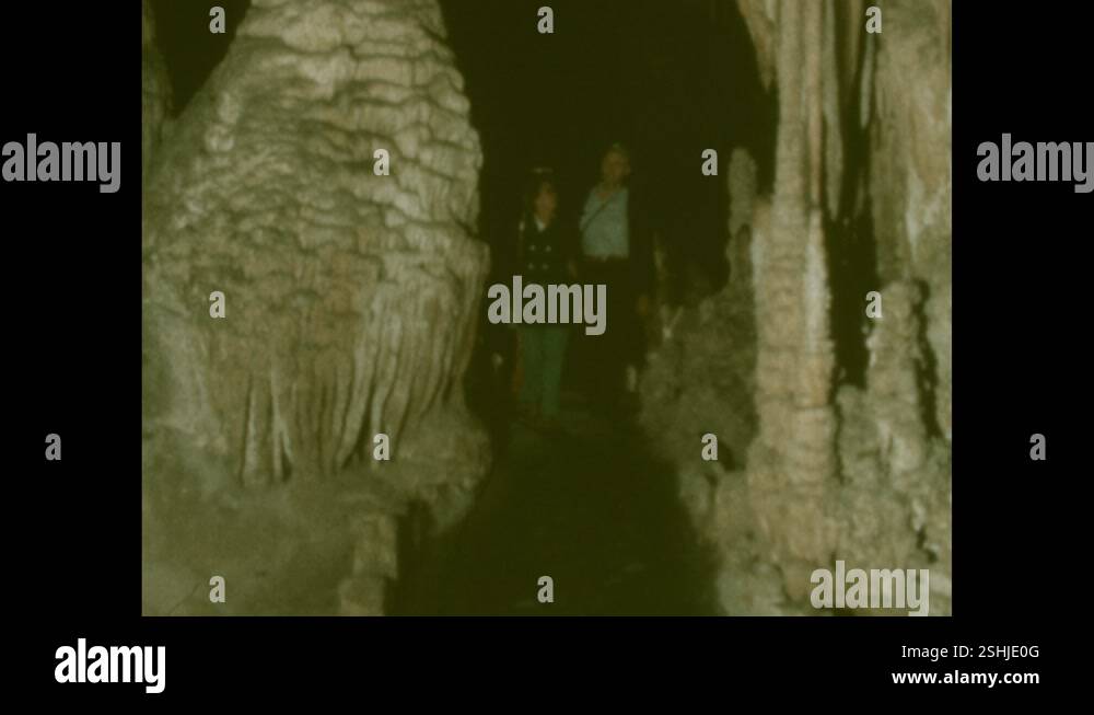 1970s: Group of people walking through cave. View of rocket taking off ...