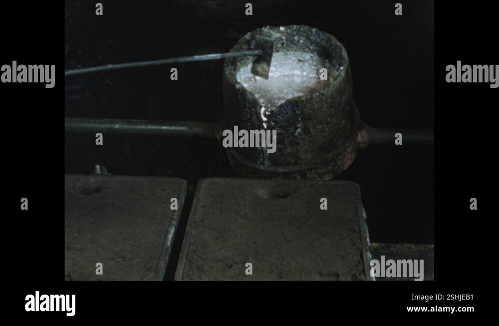 1940s: Men pour liquid silver into molds. Man uses tool to push back ...