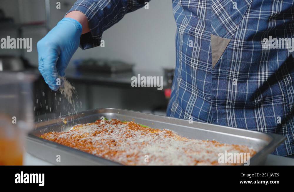 Chef sprinkling cheese on a pan of lasagna before it is cooked. Chef ...