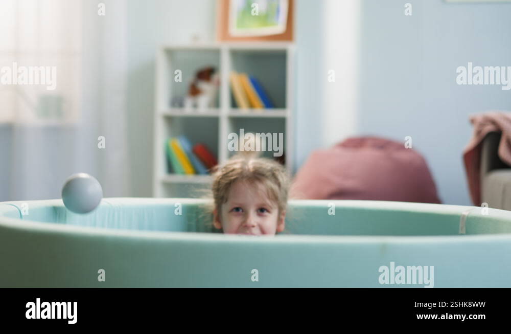 Toothless preschooler throws balls up lying in dry pool Stock Video ...