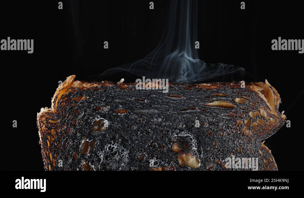 A slice of white bread is burnt, smoke is coming from it. Slow motion ...