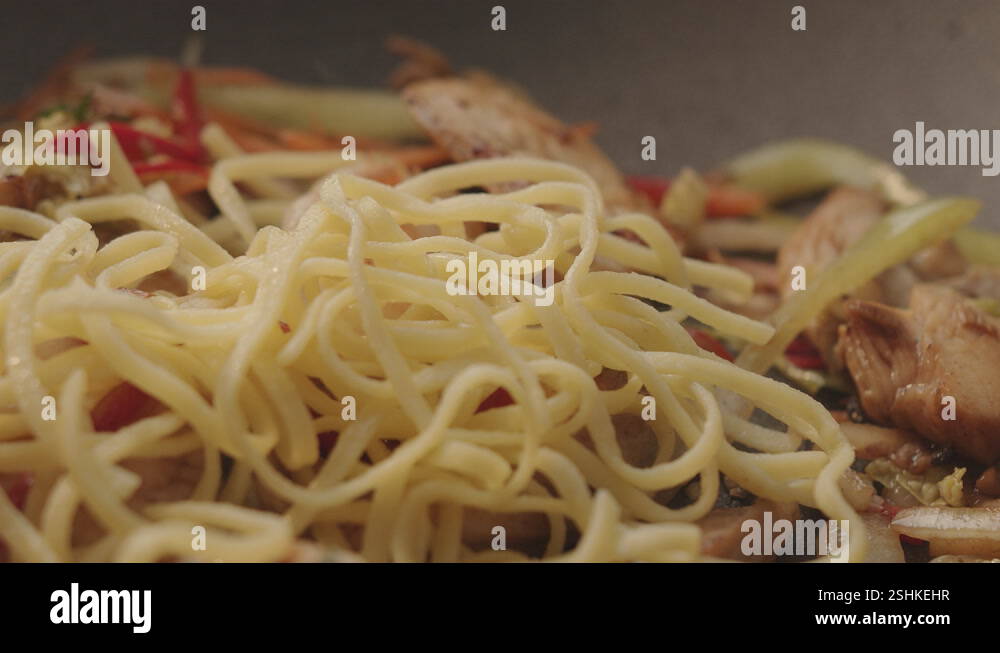 Chinese noodles, wok noodles with chicken. Process of cooking close up ...