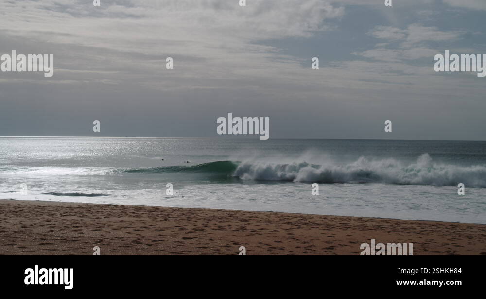 Sand beach in Nazare, Portugal, waves and few surfers, static afternoon ...