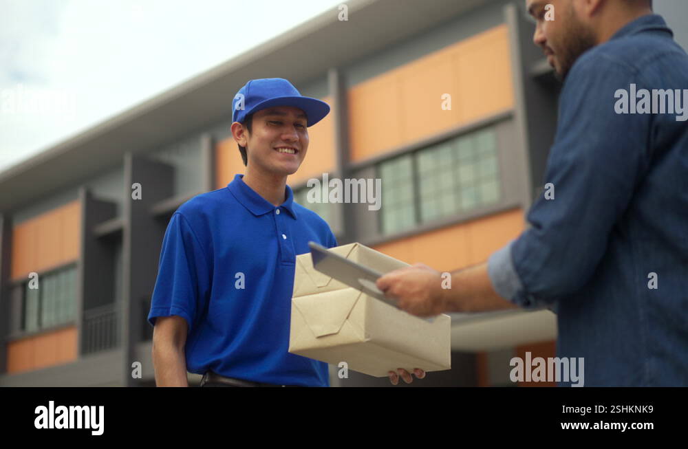 Blue uniform delivery handsome man walk and send parcel to customer ...