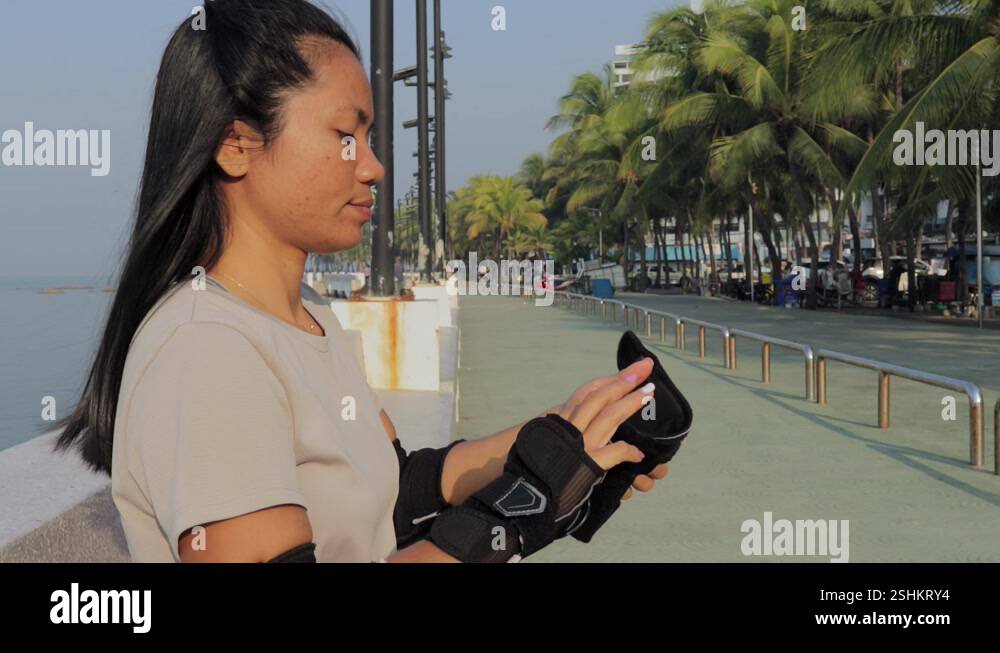 Asian Female Puts On Wrist Guard For Safe Inline Skating At The Coastal ...