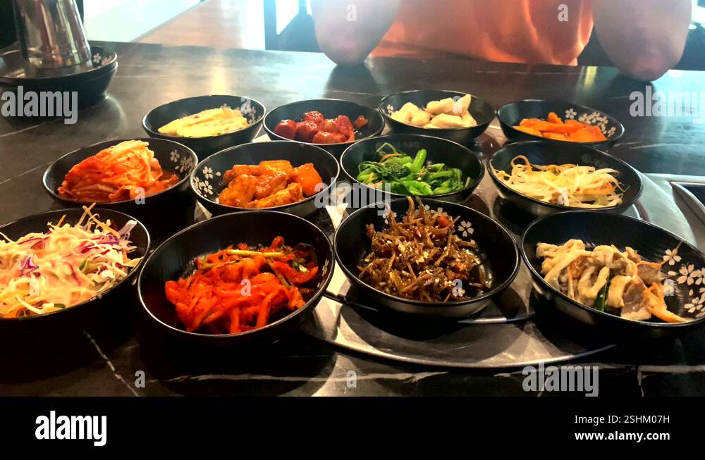 Korean-style condiments and side dishes being placed on the table Stock ...