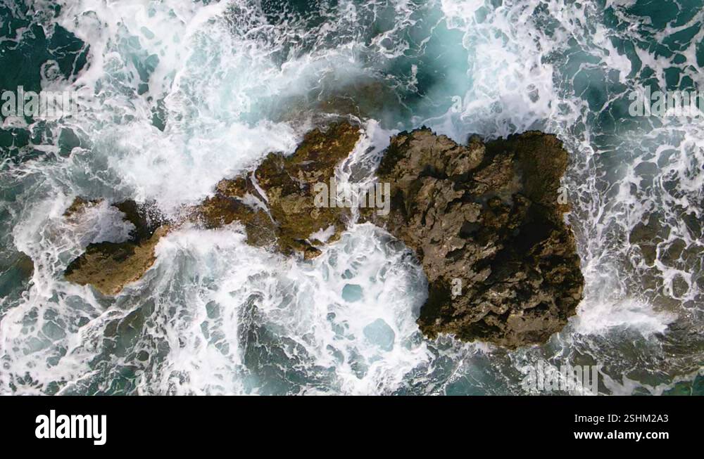 Aerial, top-down, close-up view of sea water washing rocks in 240fps ...